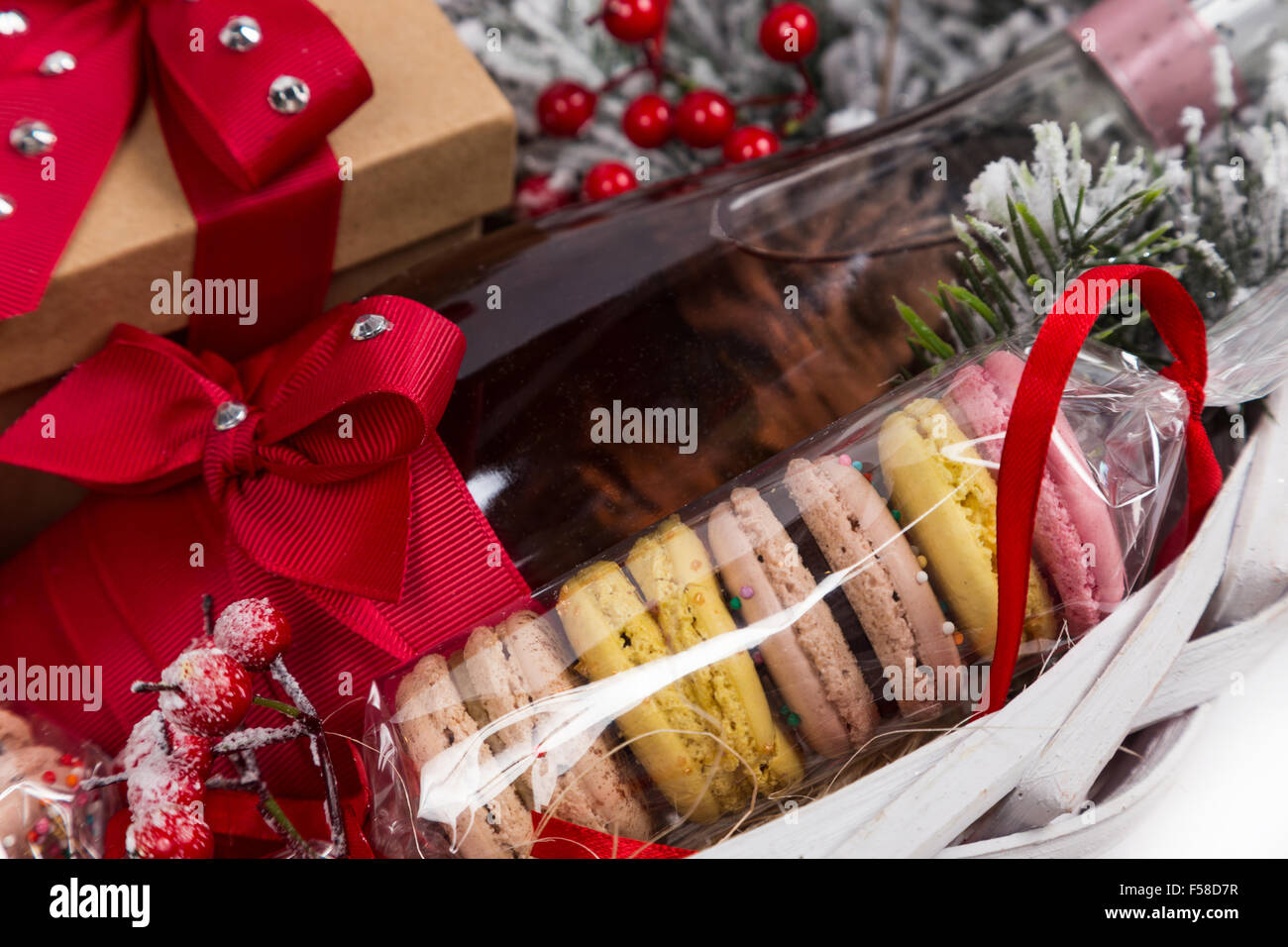 christmas present in basket with sweet pastry, bottle of wine and decor ...
