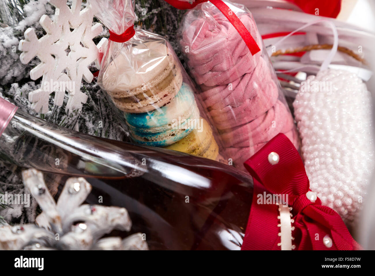 christmas present in basket with sweet pastry, bottle of wine and decor ...