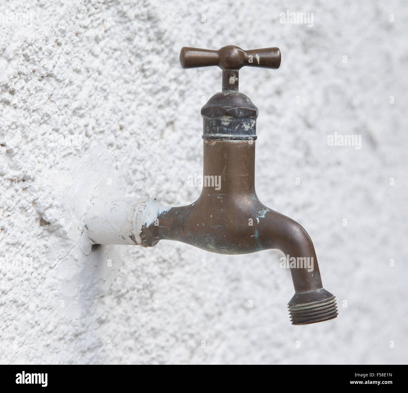 Old water tap on a white wall background Stock Photo - Alamy
