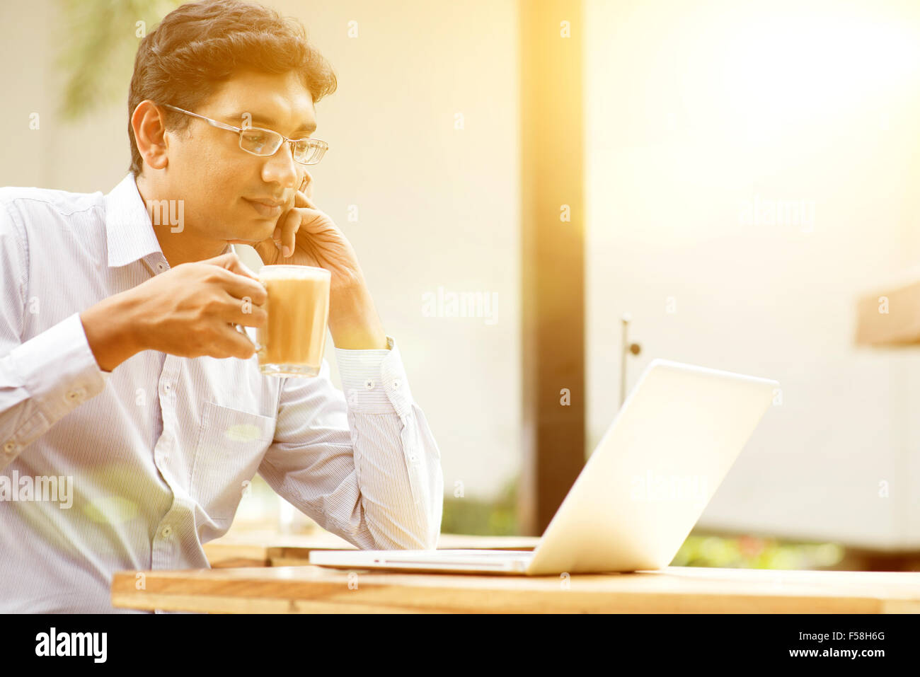 Man using laptop computer while drinking a cup hot milk tea, outdoor ...