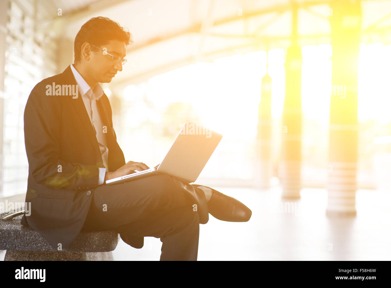 Asian Indian businessman using laptop computer while waiting train at ...