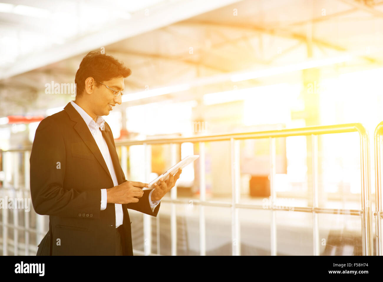 Indian business man using tablet computer while waiting train at ...