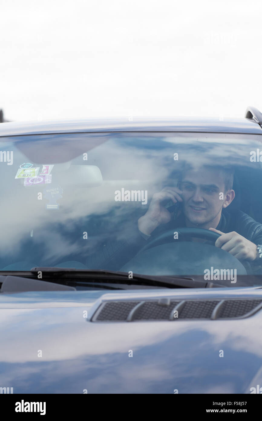 portrait of young adult behind steering wheel inside a car making a ...