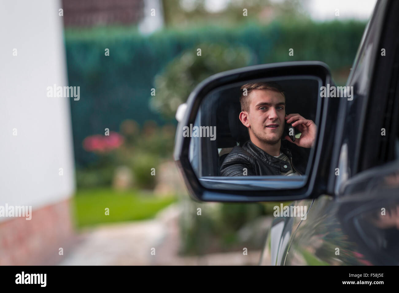 portrait of young adult behind steering wheel inside a car making a ...