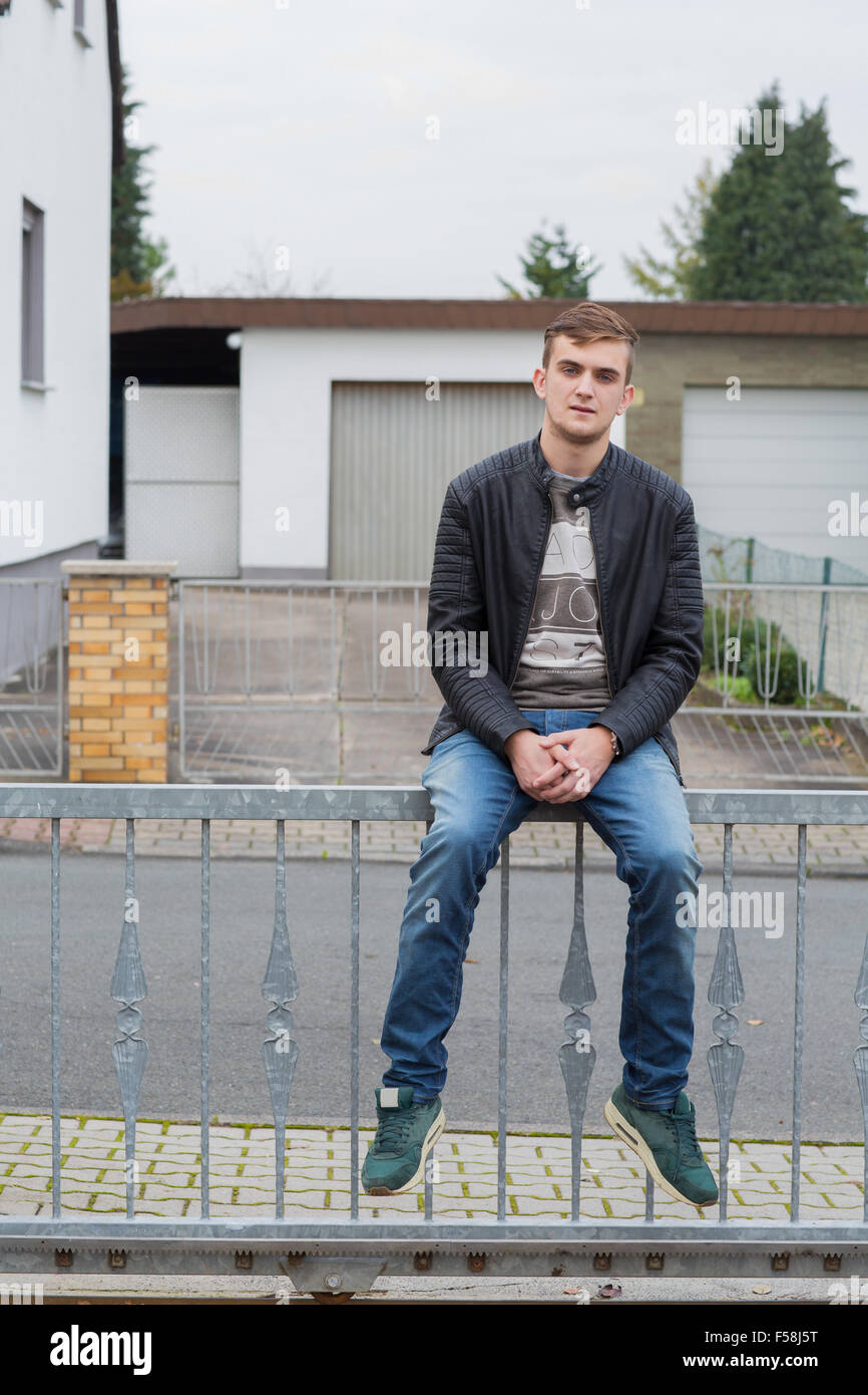 Young man sitting on fence hi-res stock photography and images - Alamy