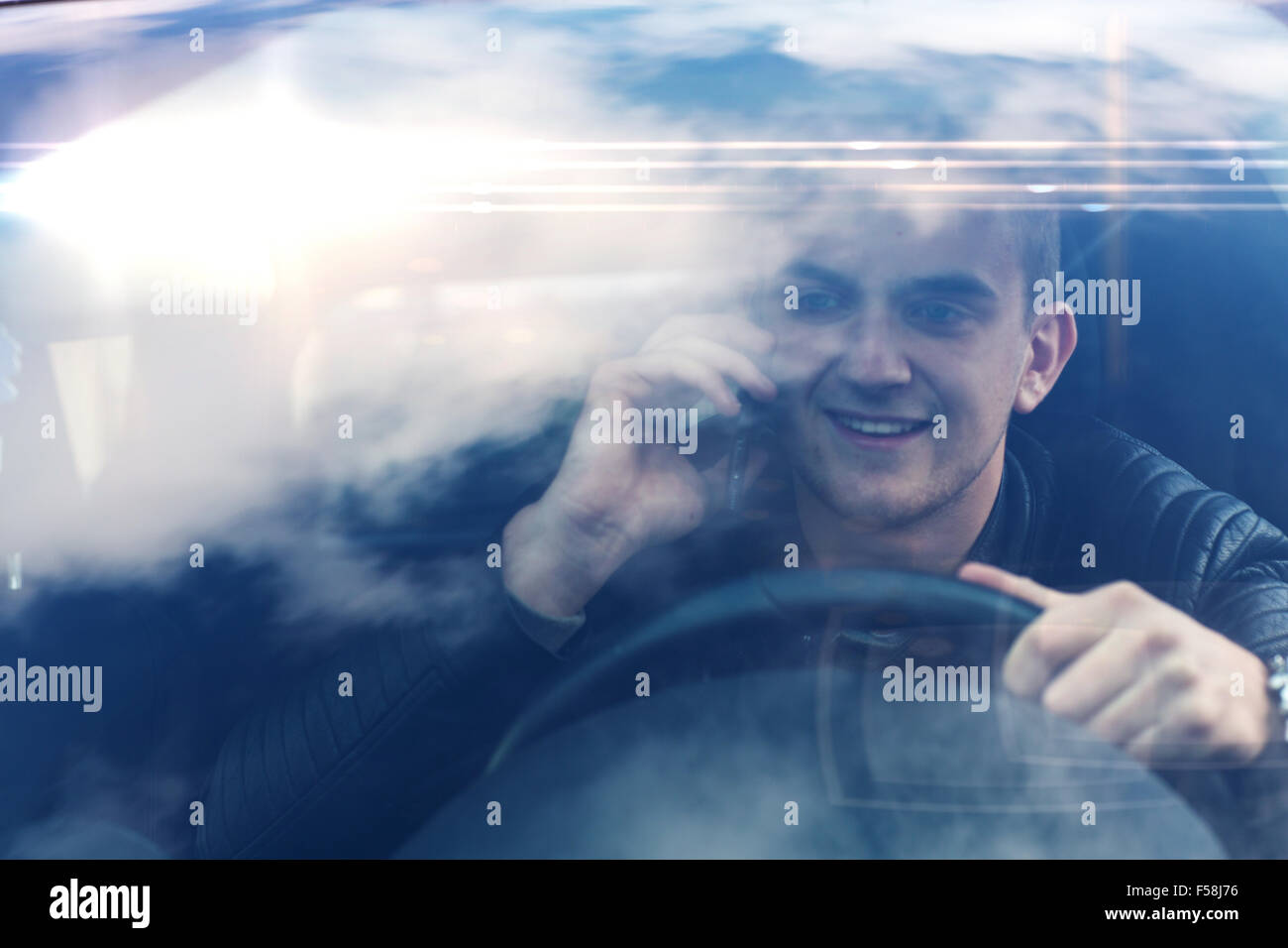 portrait of young adult behind steering wheel inside a car making a ...