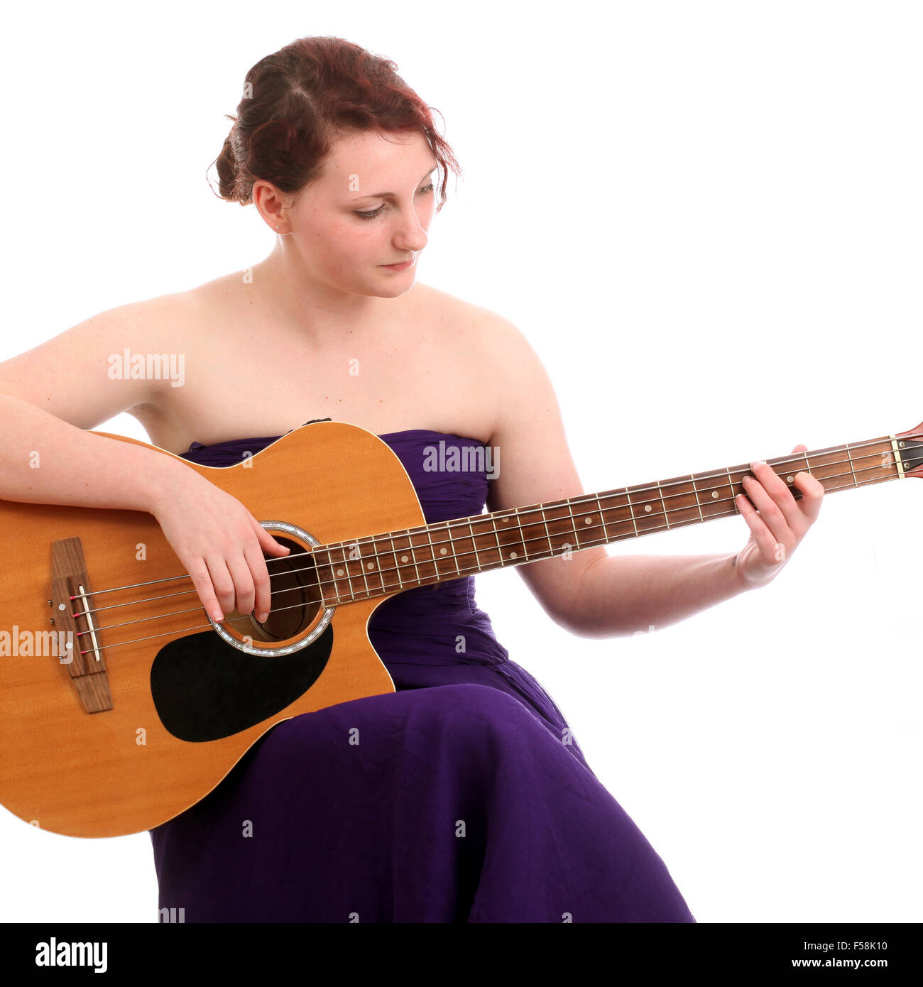 Beautiful teenage girl playing her acoustic bass guitar in a purple ...