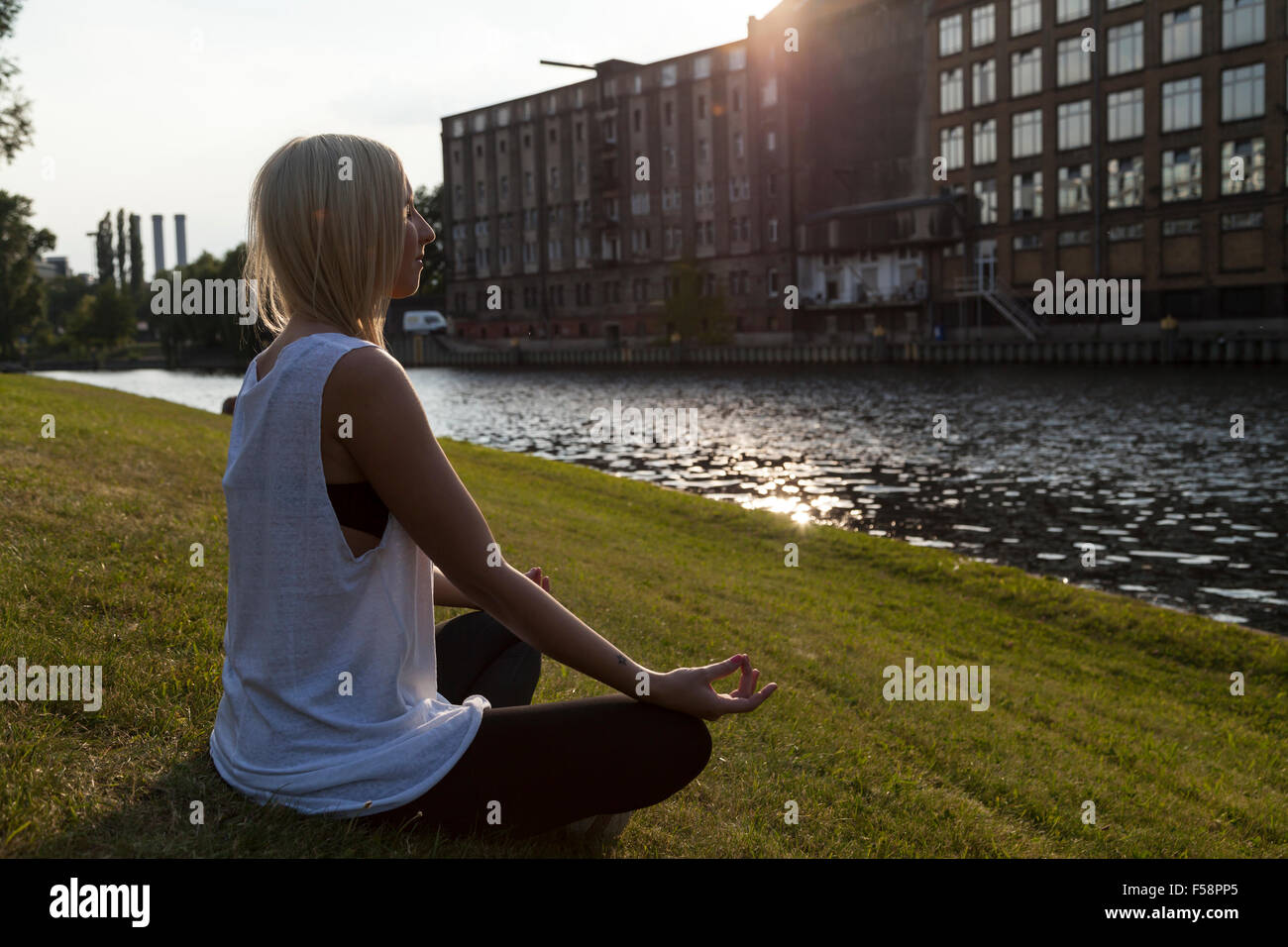 Woman doing yoga (lotus position) in Berlin at Spree Stock Photo - Alamy
