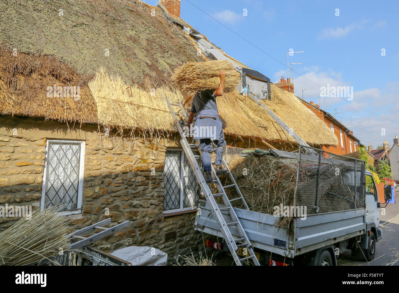 Skilled thatchers at work restoring a thatched roof on a cottage in ...