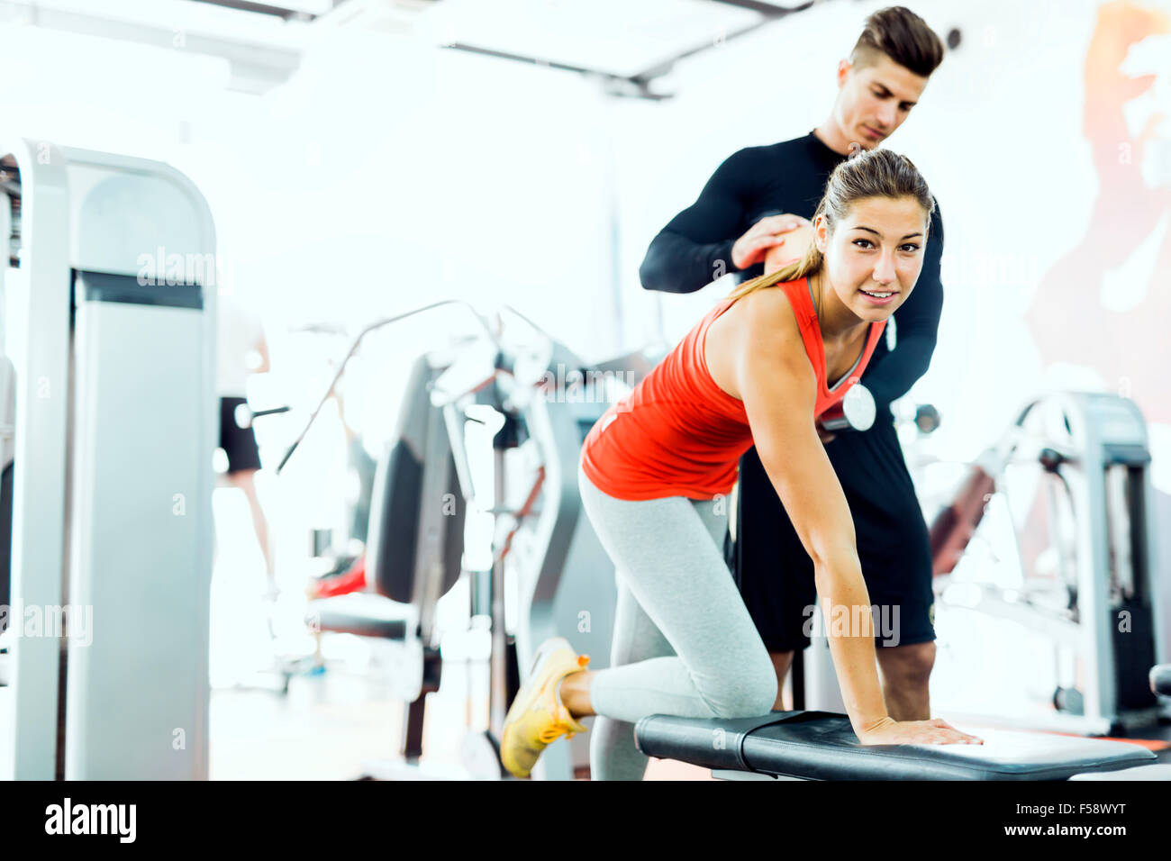 Young male trainer giving instructions to a woman in a gym and being ...