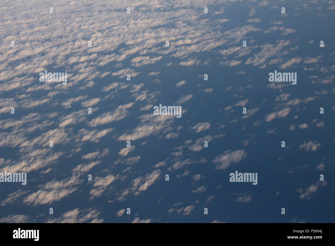 Blue sky with gray white clouds shot from airplane window in flight ...