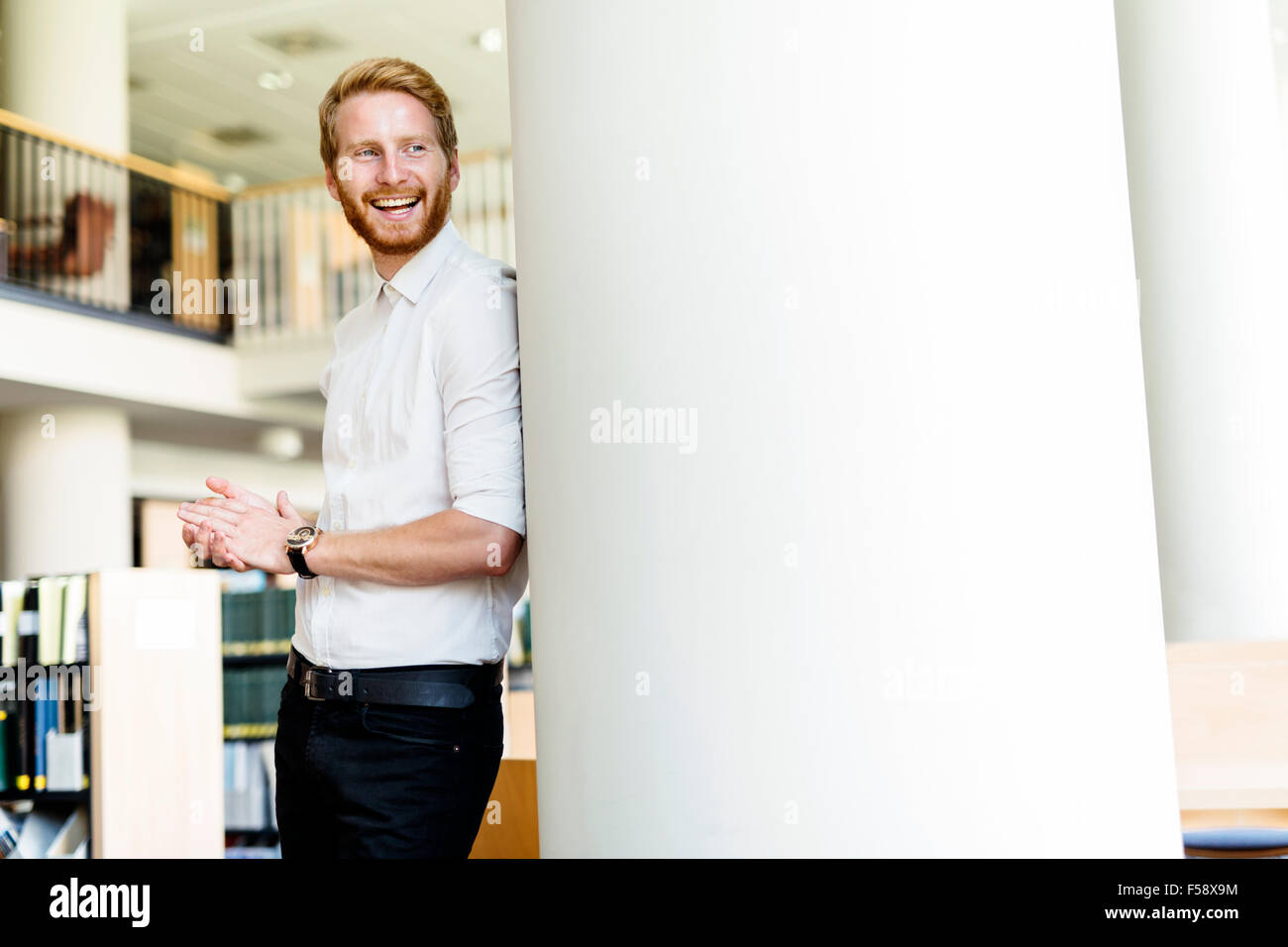 Handsome intelligent male student smiling in library Stock Photo - Alamy