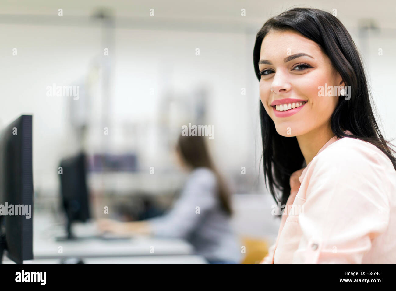 Young beautiful woman smiling happily in a classroom equipped with ...