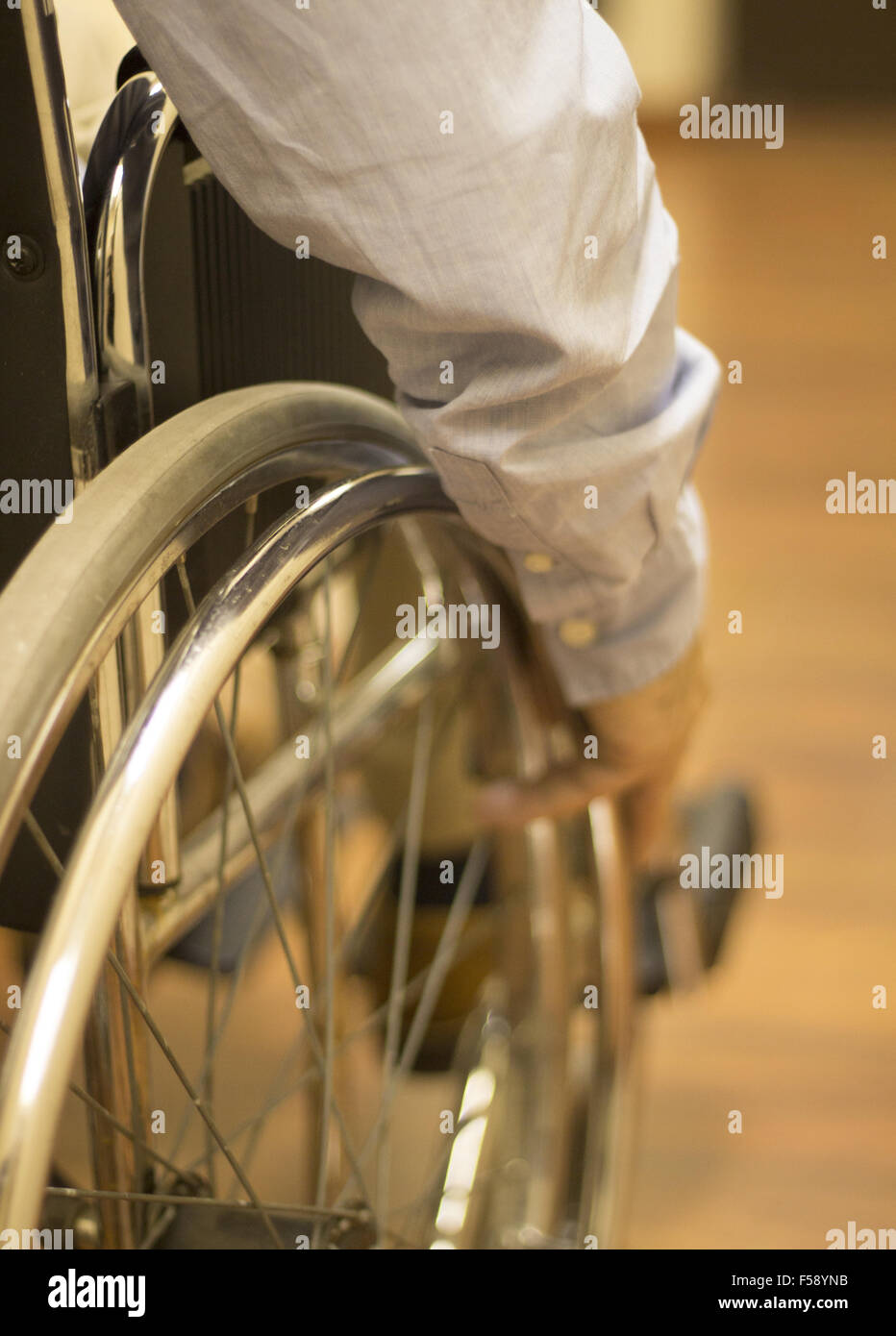 Man sitting in wheel chair wearing blue shirt pushing wheel to move ...