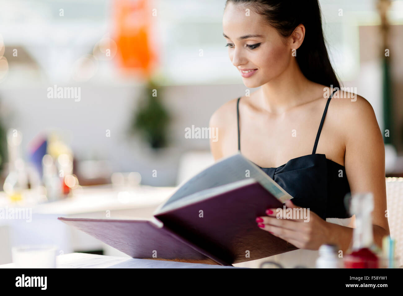 Beautiful woman ordering from menu in restaurant and deciding what to ...
