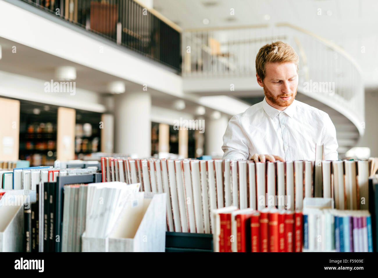 Handsome student searching for a book in a beautiful library Stock ...