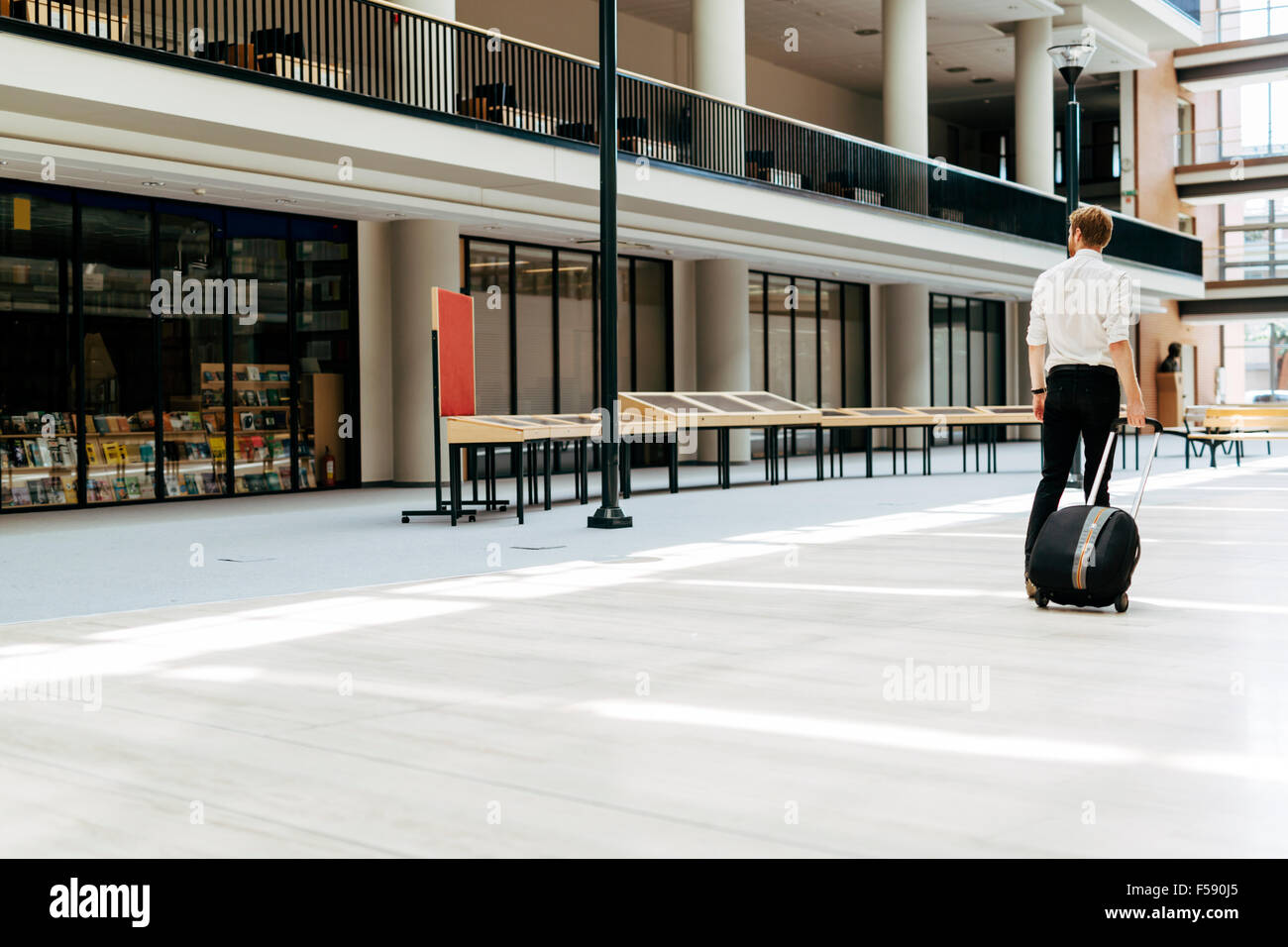 Handsome business holding a trolley and walking in a modern building ...
