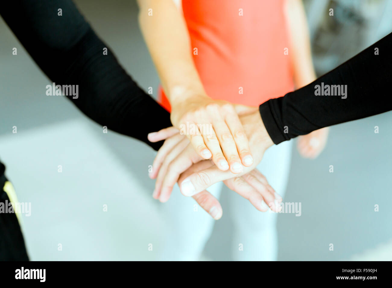 Three hands placed on top of each other between sportsmen as a sign of ...