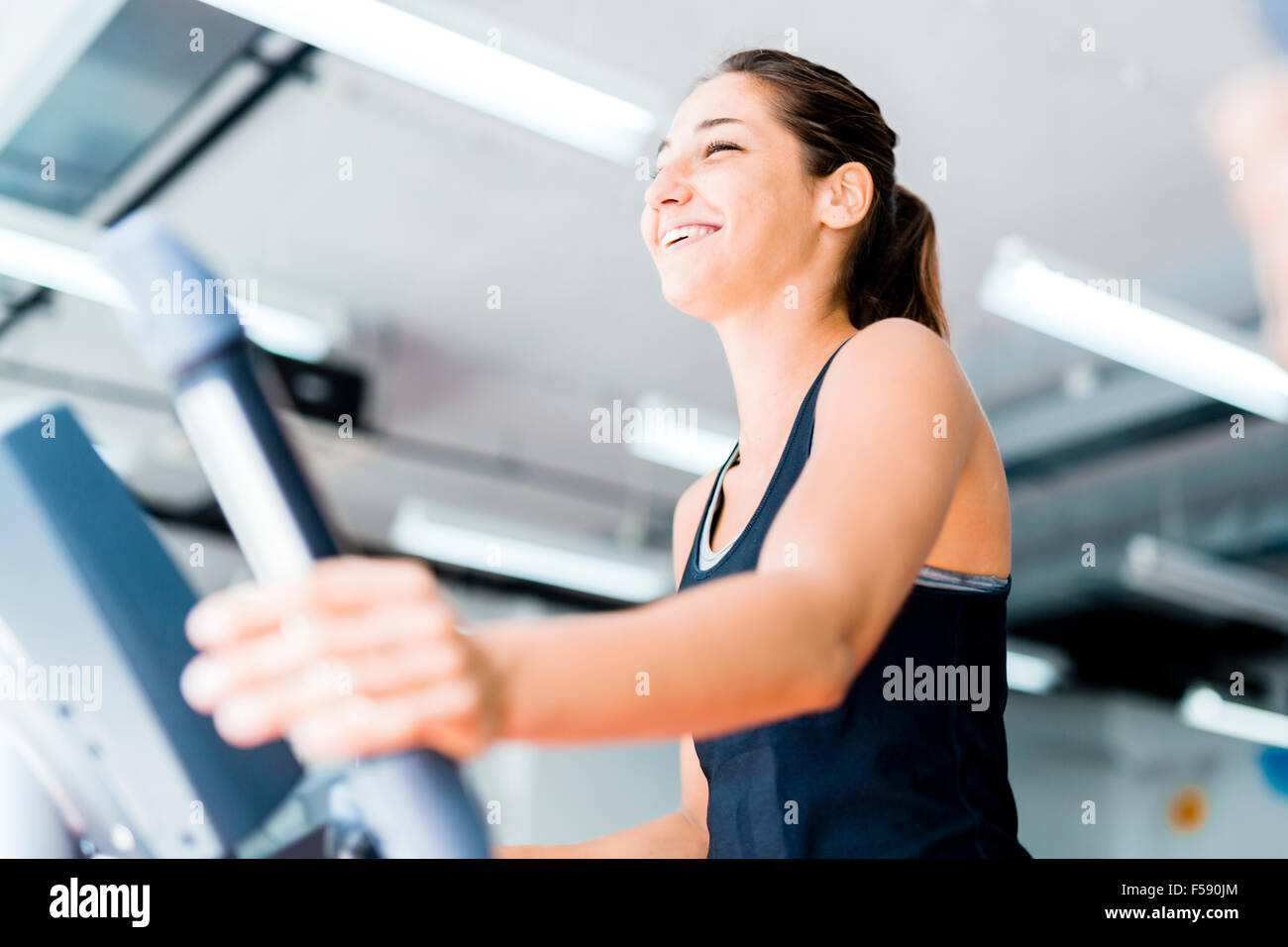 Beautiful young lady using the elliptical trainer in a gym in a ...