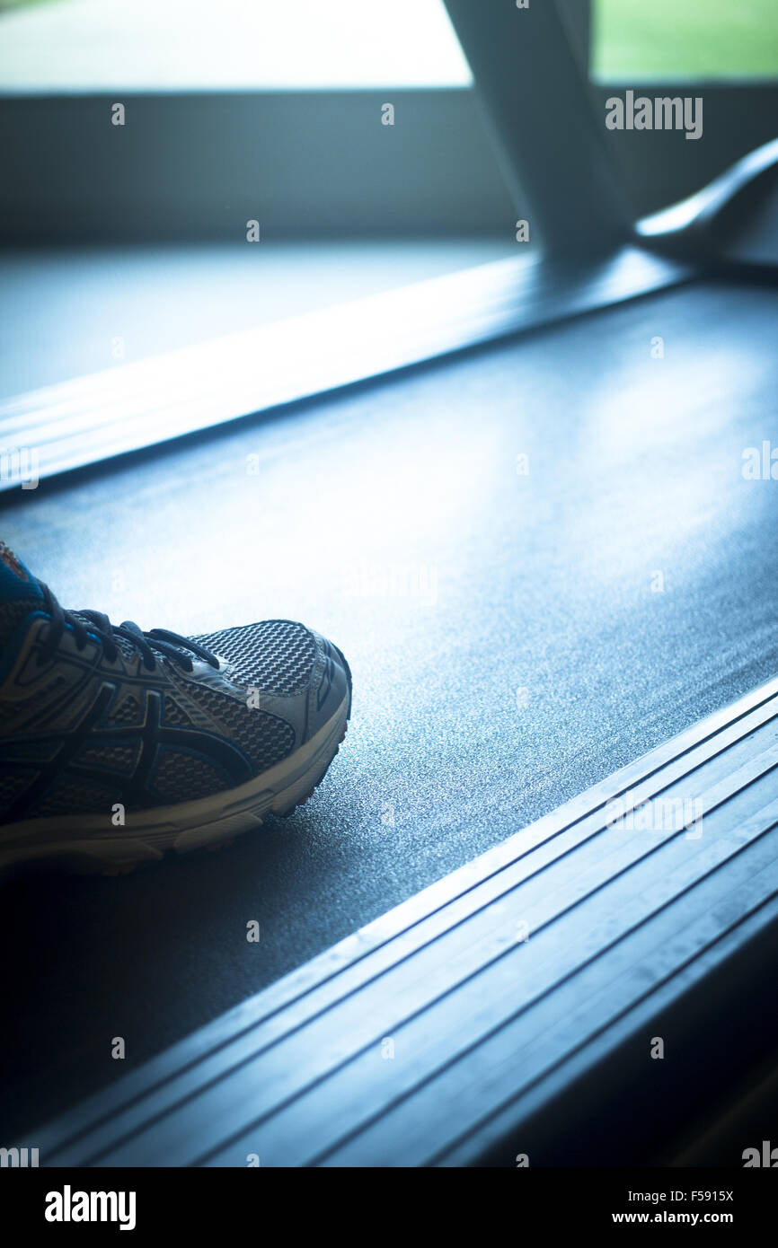 Running machine and runner in sports shoes trainers in exercise room in ...