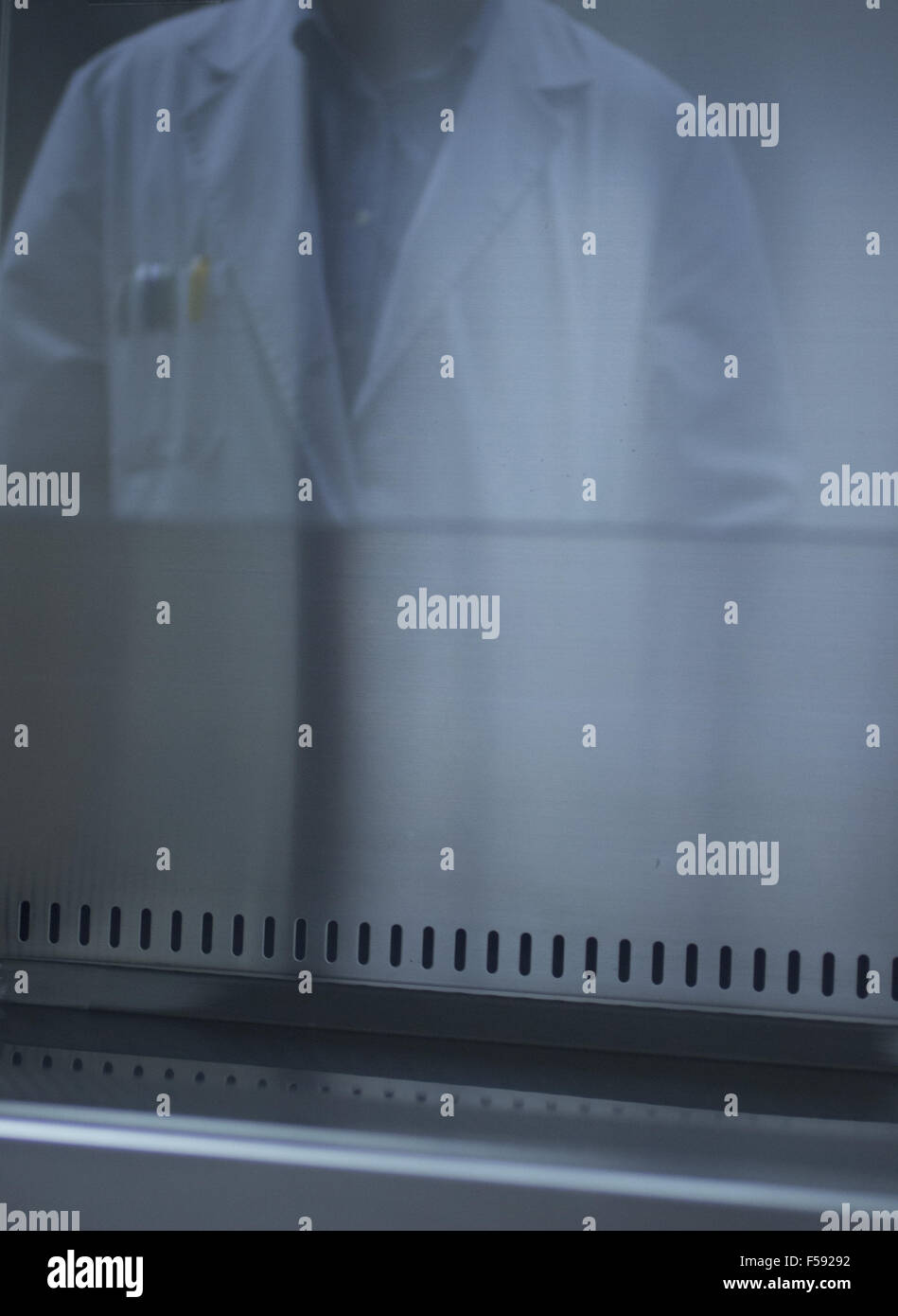 Reflection in laboratory of male lab technician in labcoat and blue ...