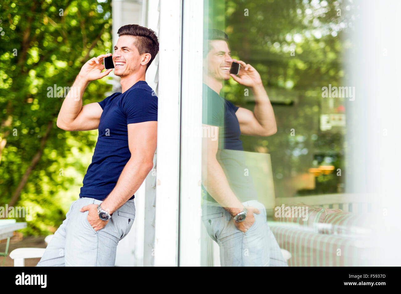 Handsome man talking on the phone outdoors and his reflection is ...