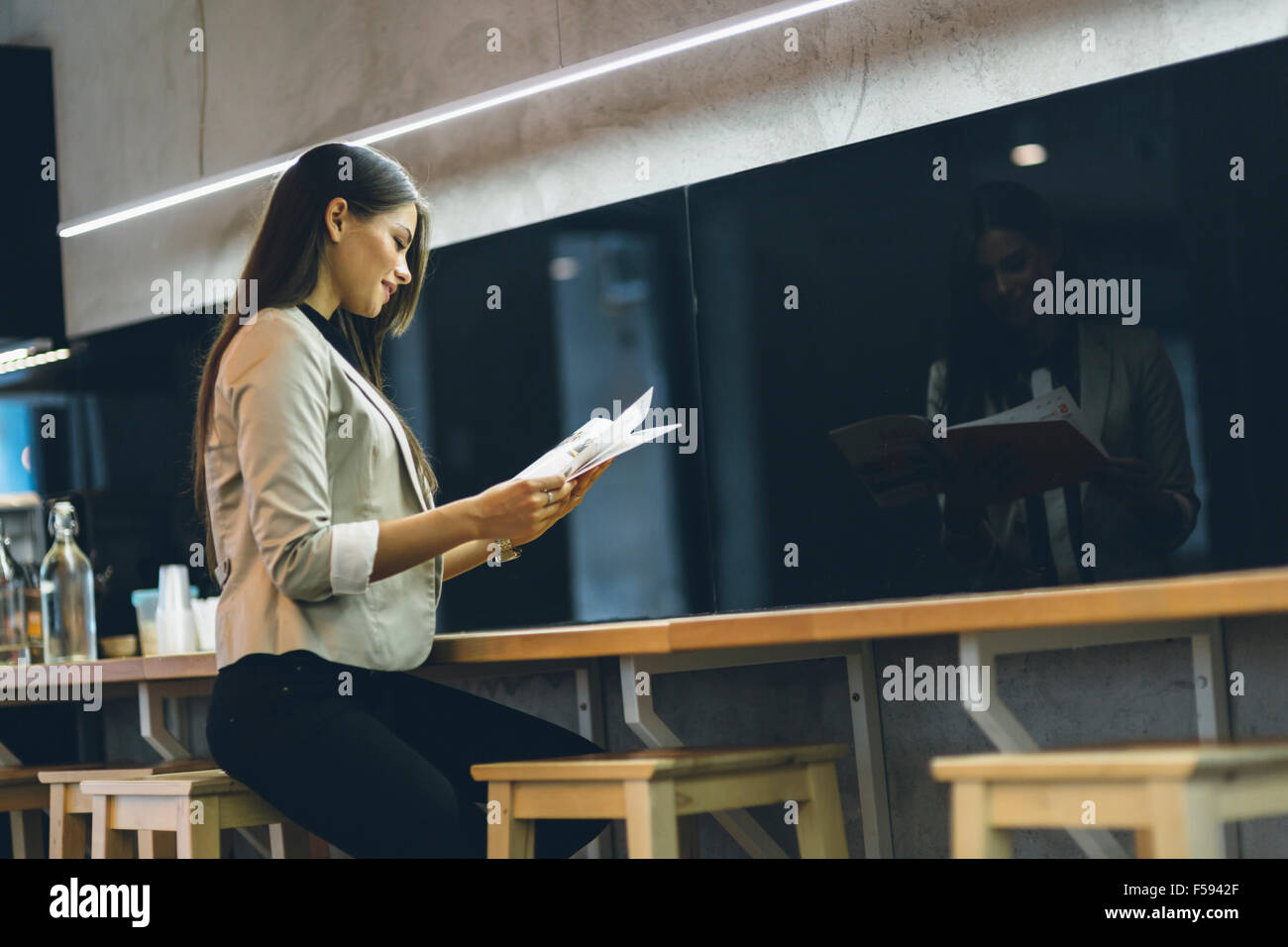 Beautiful woman reading the menu on a counter of a bar Stock Photo - Alamy