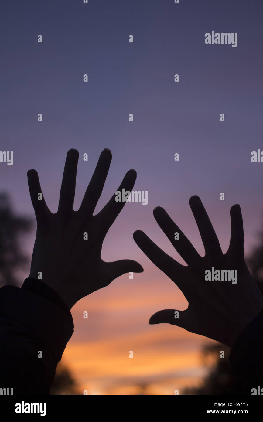 Fingers of hands at dusk silhouette sunset sky at dusk in countryside ...