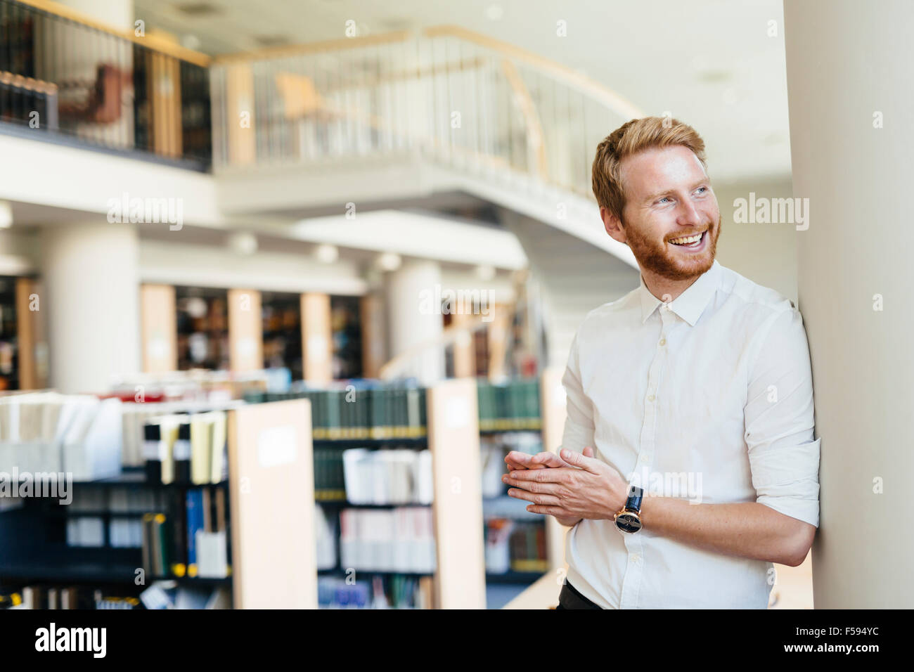 Handsome intelligent male student smiling in library Stock Photo - Alamy