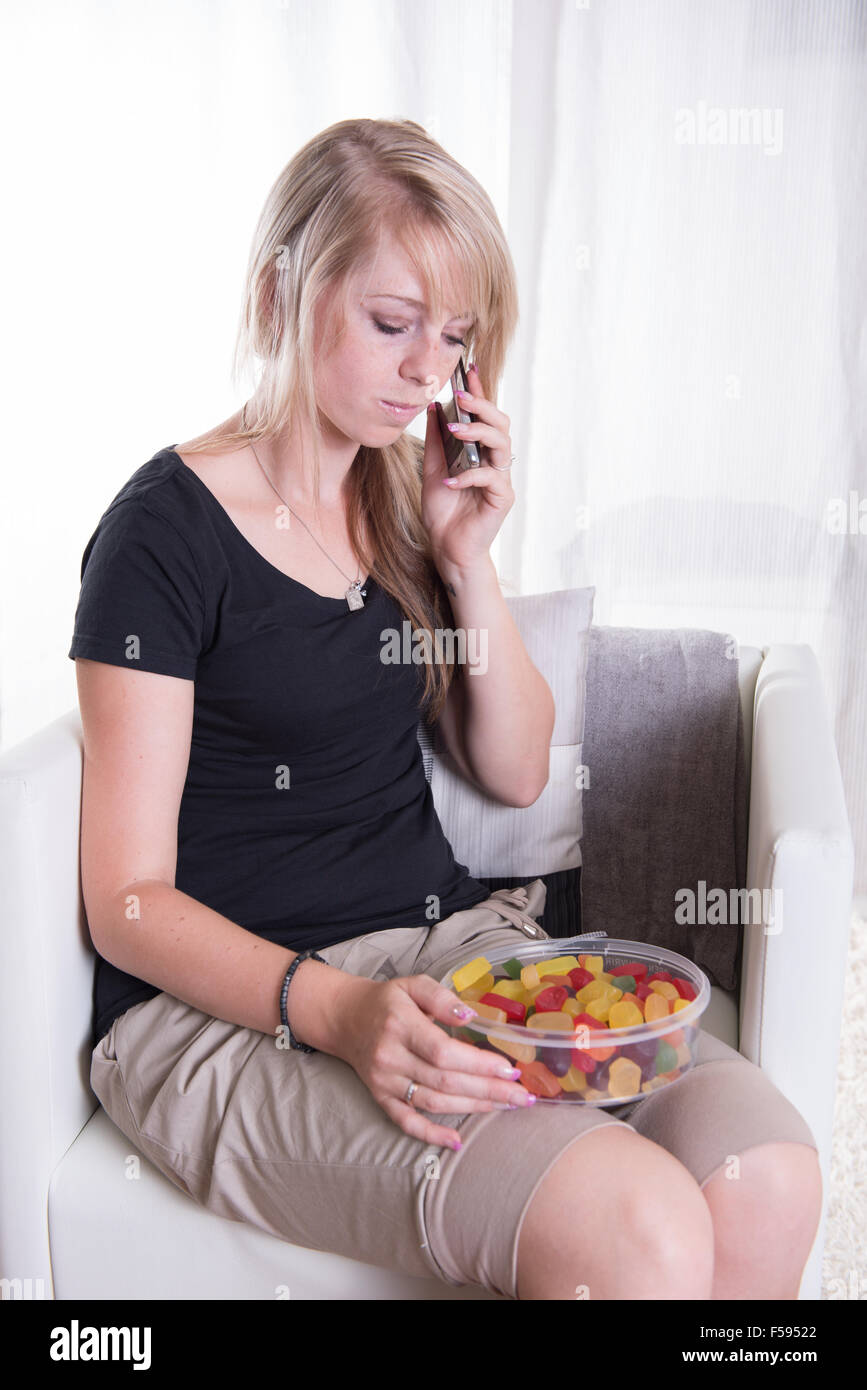 young woman on the phone eating sweets Stock Photo - Alamy
