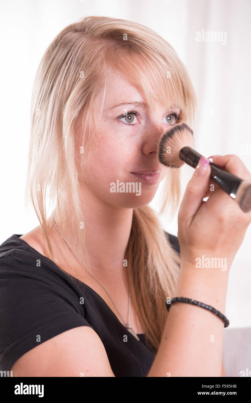 young woman putting powder with a brush on her nose Stock Photo - Alamy