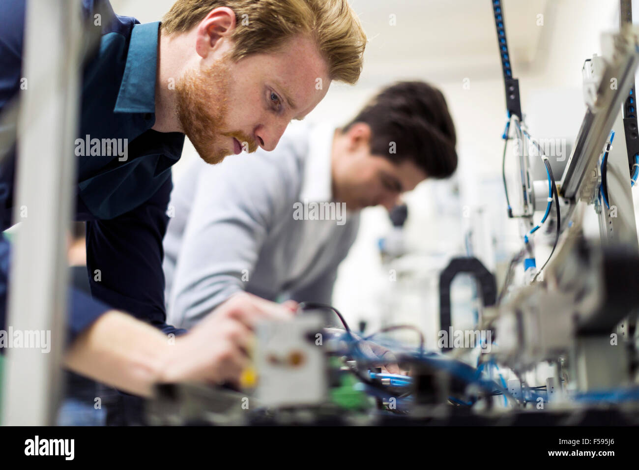 Two young handsome engineers working on electronics components and ...