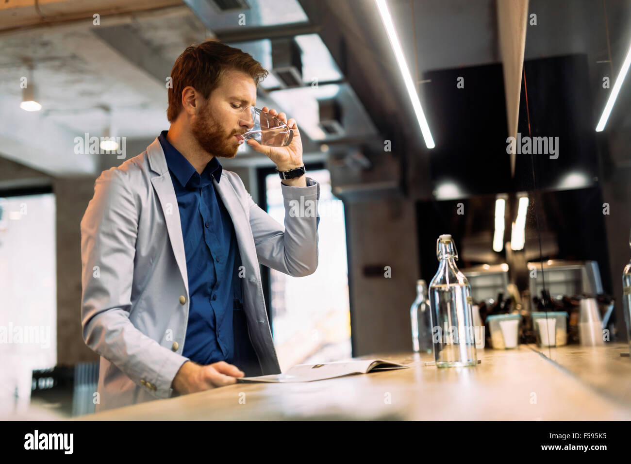 Businessman drinking water and reading paper during break Stock Photo ...