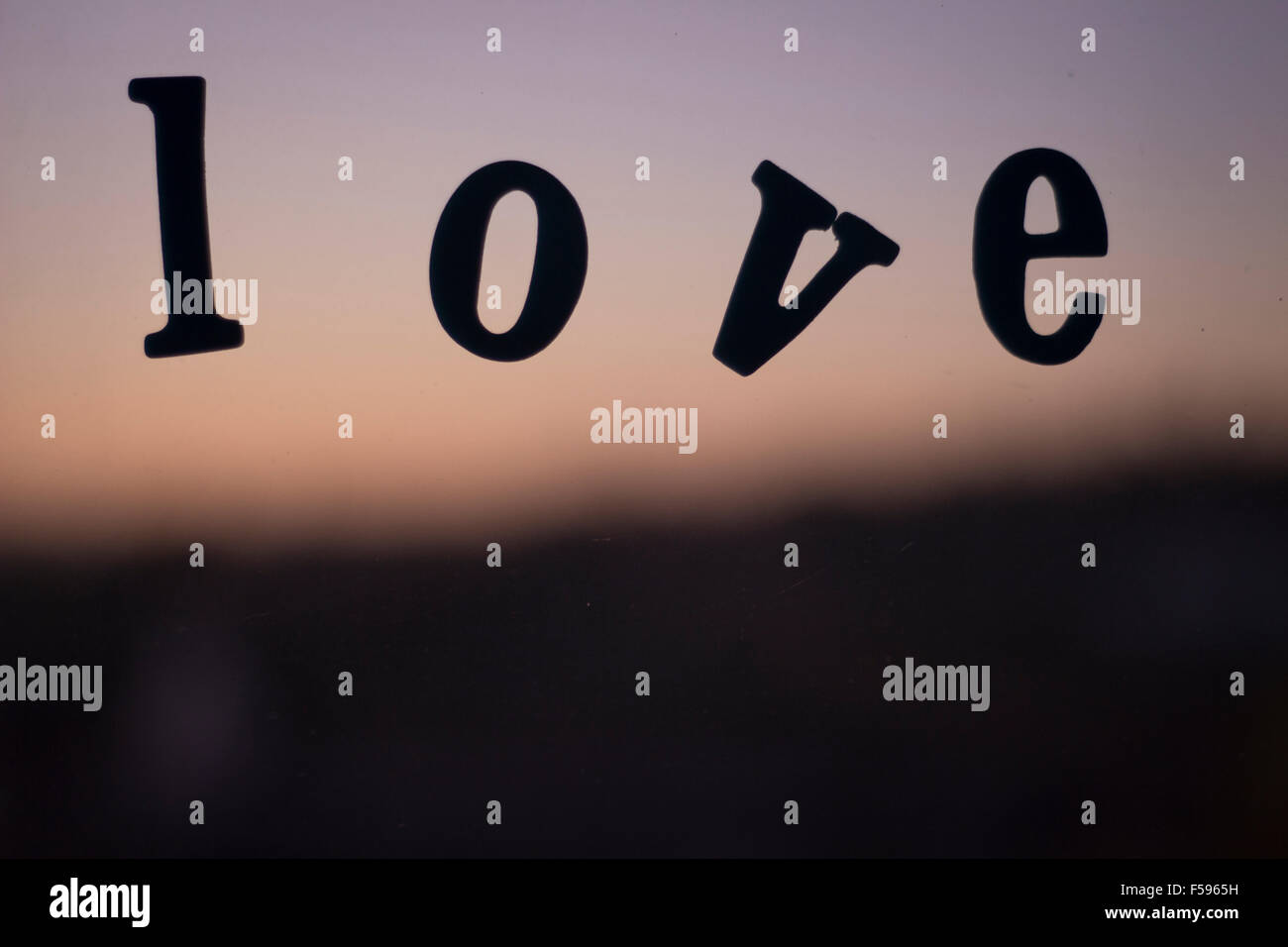 The word love spelled in letters on a glass window pain with background ...