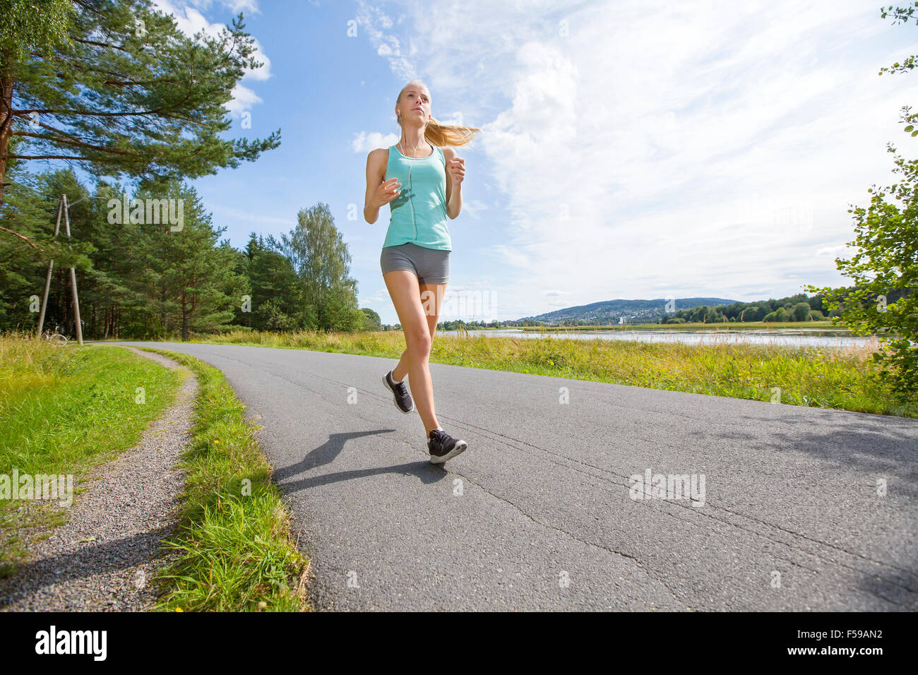 Motivated woman runs fast on a road in the forest Stock Photo - Alamy