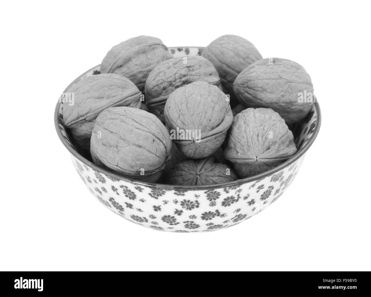 Walnuts in shells, in a porcelain bowl with a floral design, isolated ...
