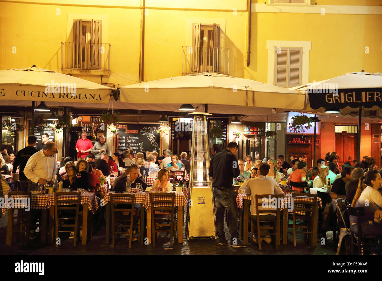 Diners enjoying eating outdoors at restaurants during summer in Rome ...