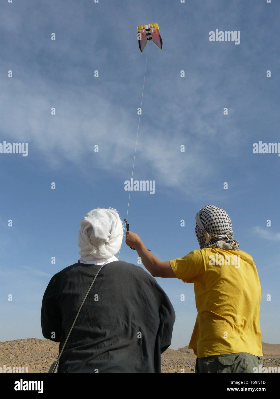 two friends holding a flying kite together Stock Photo - Alamy