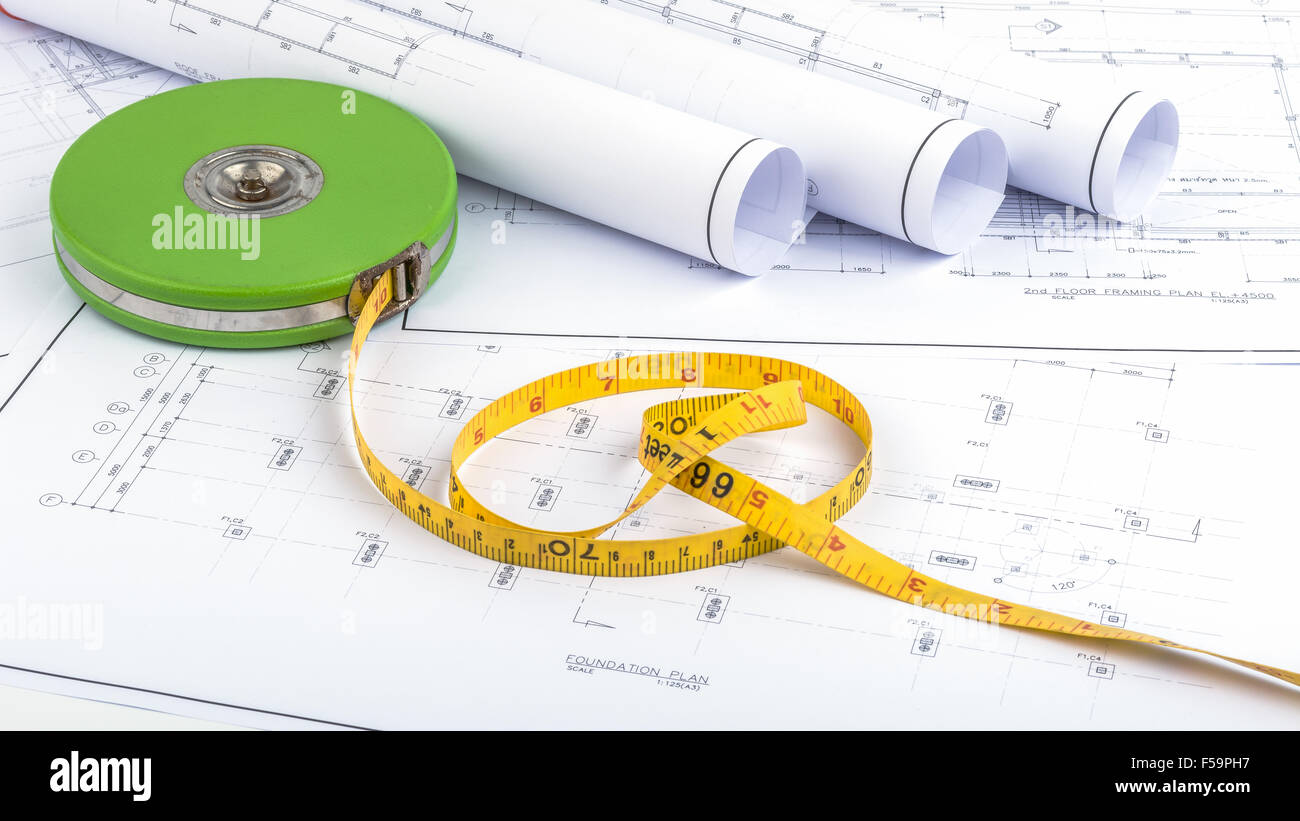 Tape measure placed on the desk, filled with building plans. In order ...