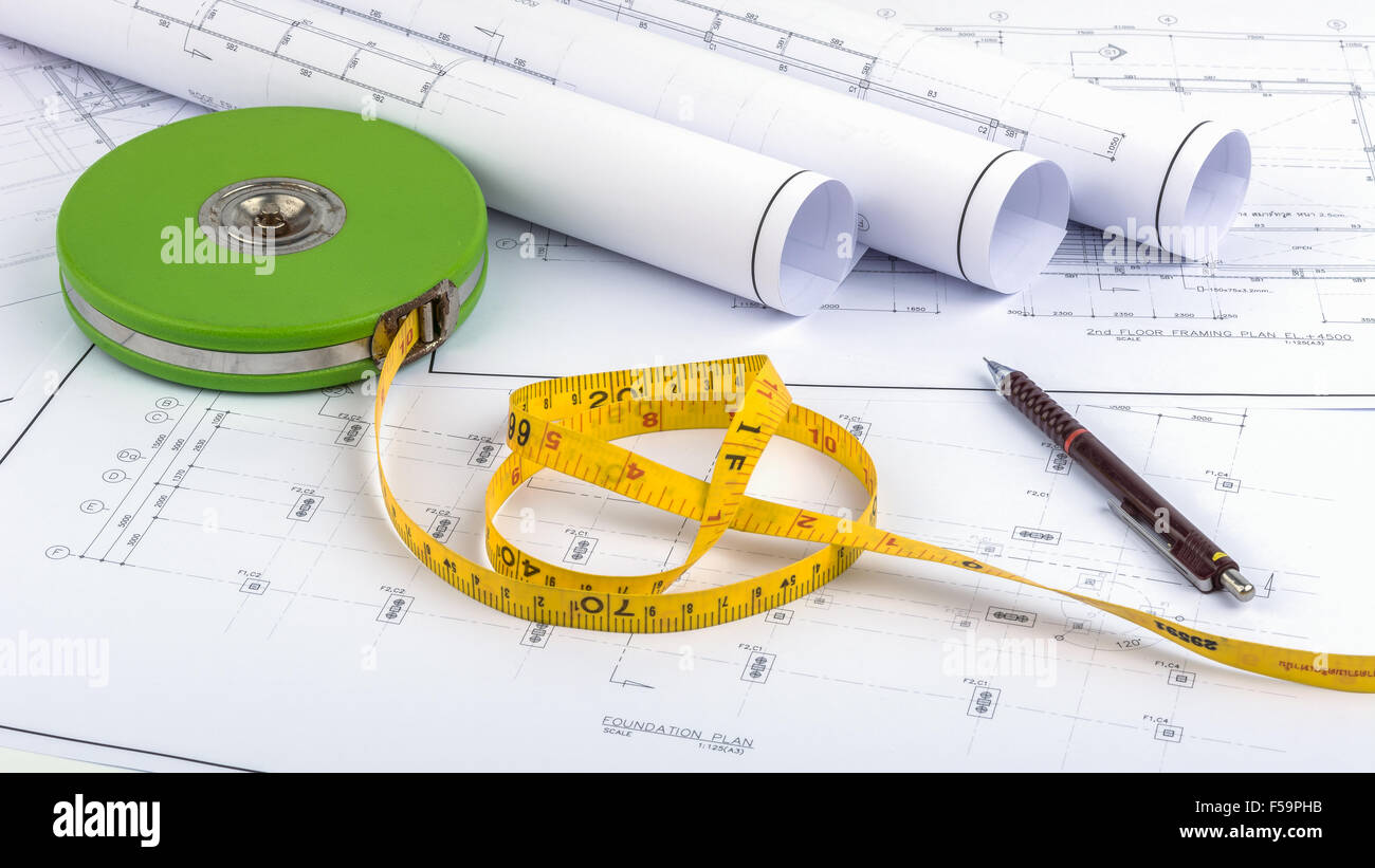 Tape measure and pen placed on the desk, filled with building plans. In ...