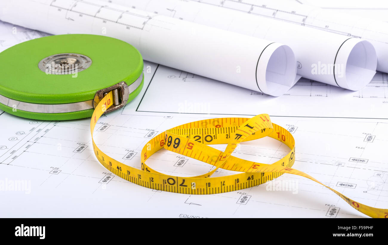 Tape measure placed on the desk, filled with building plans. In order ...