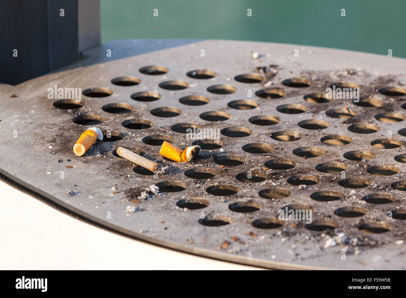 Smoked cigarettes in a dirty outdoors ash-tray. Closeup shot with a ...