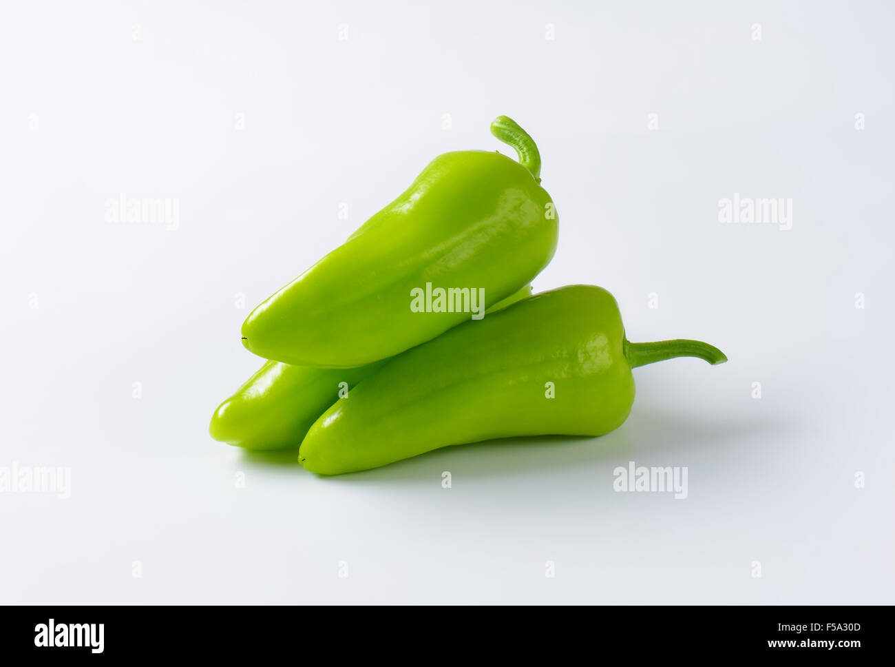 Three green peppers on white background Stock Photo - Alamy
