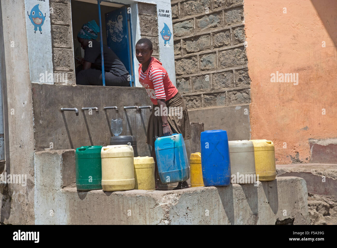 Woman with water containers collecting affordable treated drinking ...