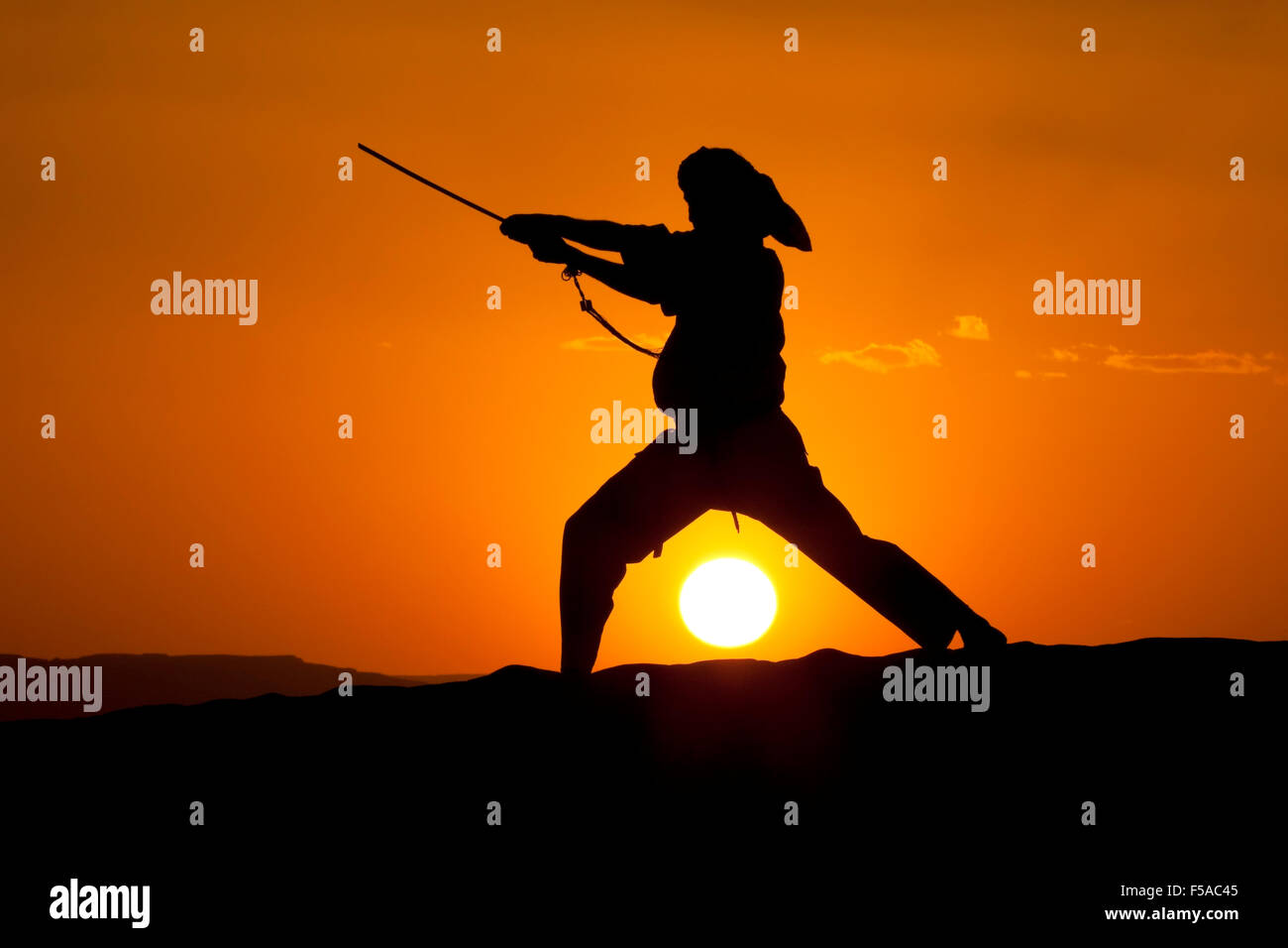 A man practices karate with a sword against a sunset Stock Photo - Alamy