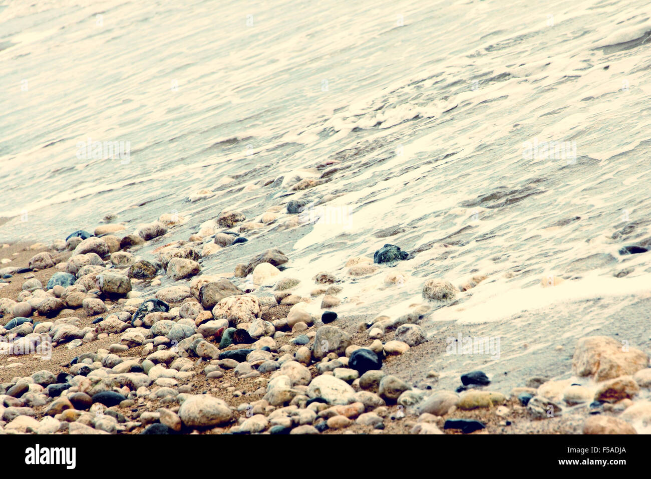 Sea surf and vivid coastal stones.Toned image Stock Photo - Alamy