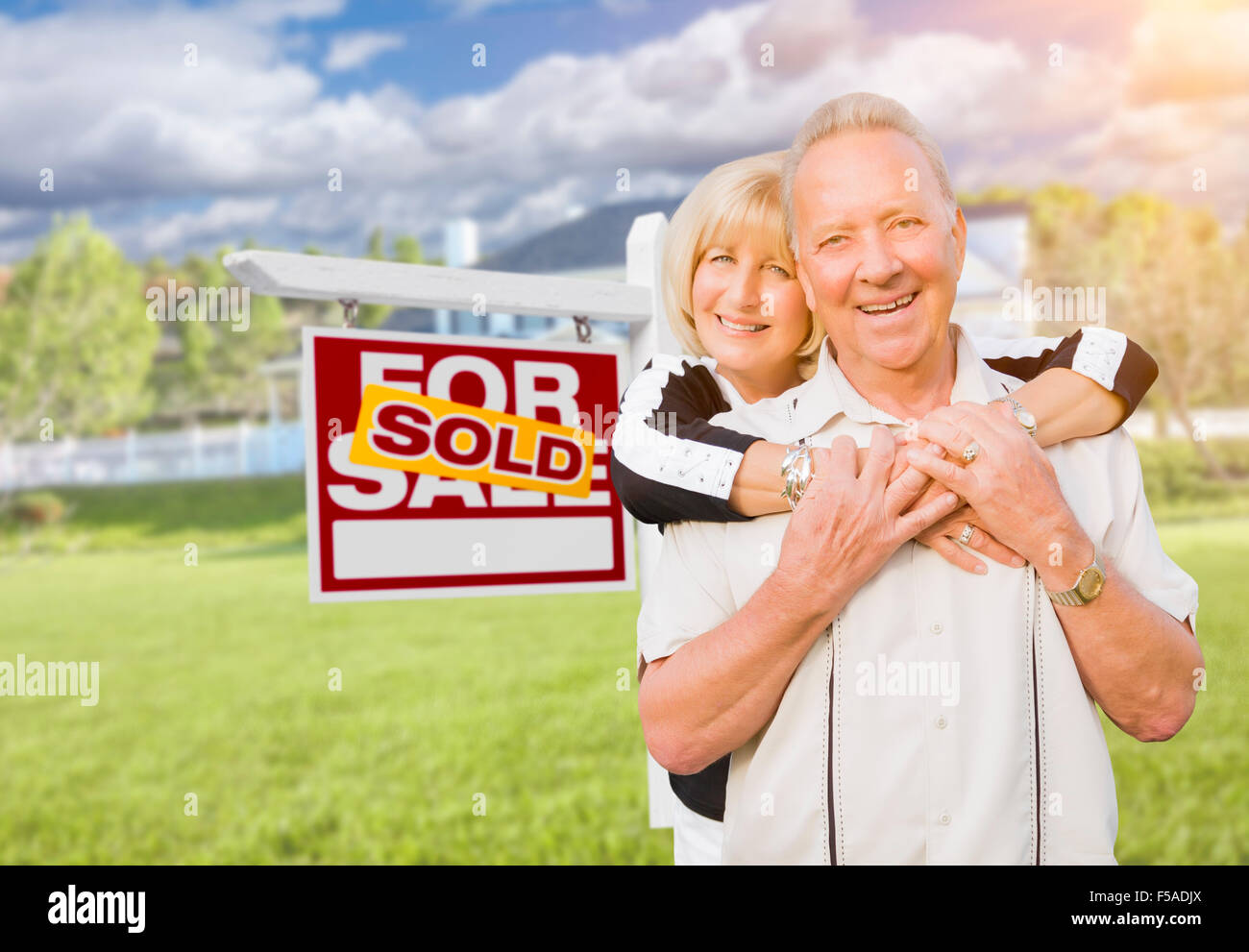 Happy Affectionate Senior Couple Hugging in Front of Sold Real Estate ...
