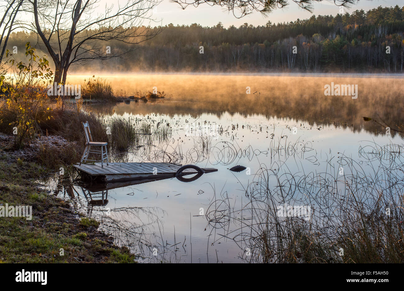 October morning on lake with a dock and chair at the lakeside Stock ...