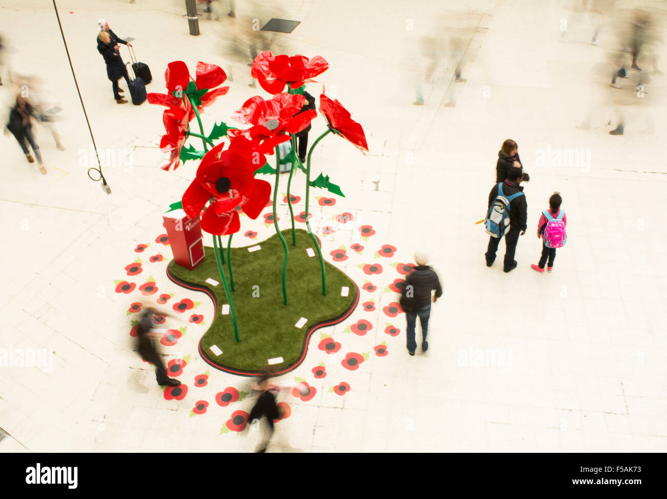 People swirling past a giant poppy installation on the concourse of ...