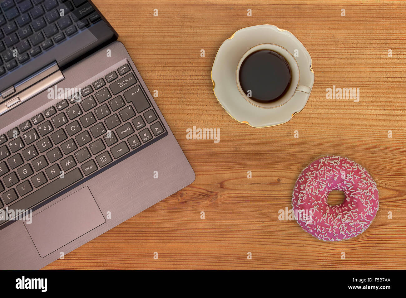 Coffee break, snack or breakfast at work. Donut, coffee and computer on ...